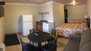 Quarto compacto com cozinha compacta, mesa de jantar com cadeiras, sofá e duas camas.
