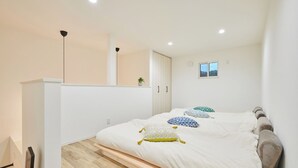 Um quarto com cama, almofadas, janela e porta.