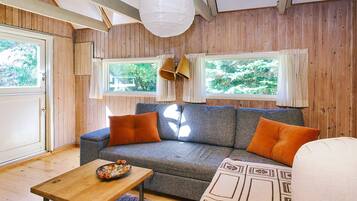 Uma sala de estar aconchegante com um sofá, uma mesa e uma janela com cortinas.
