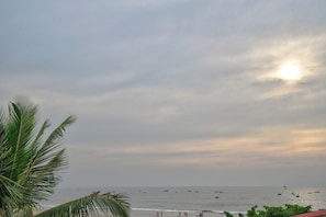 Uma praia com palmeiras, oceano e barcos.