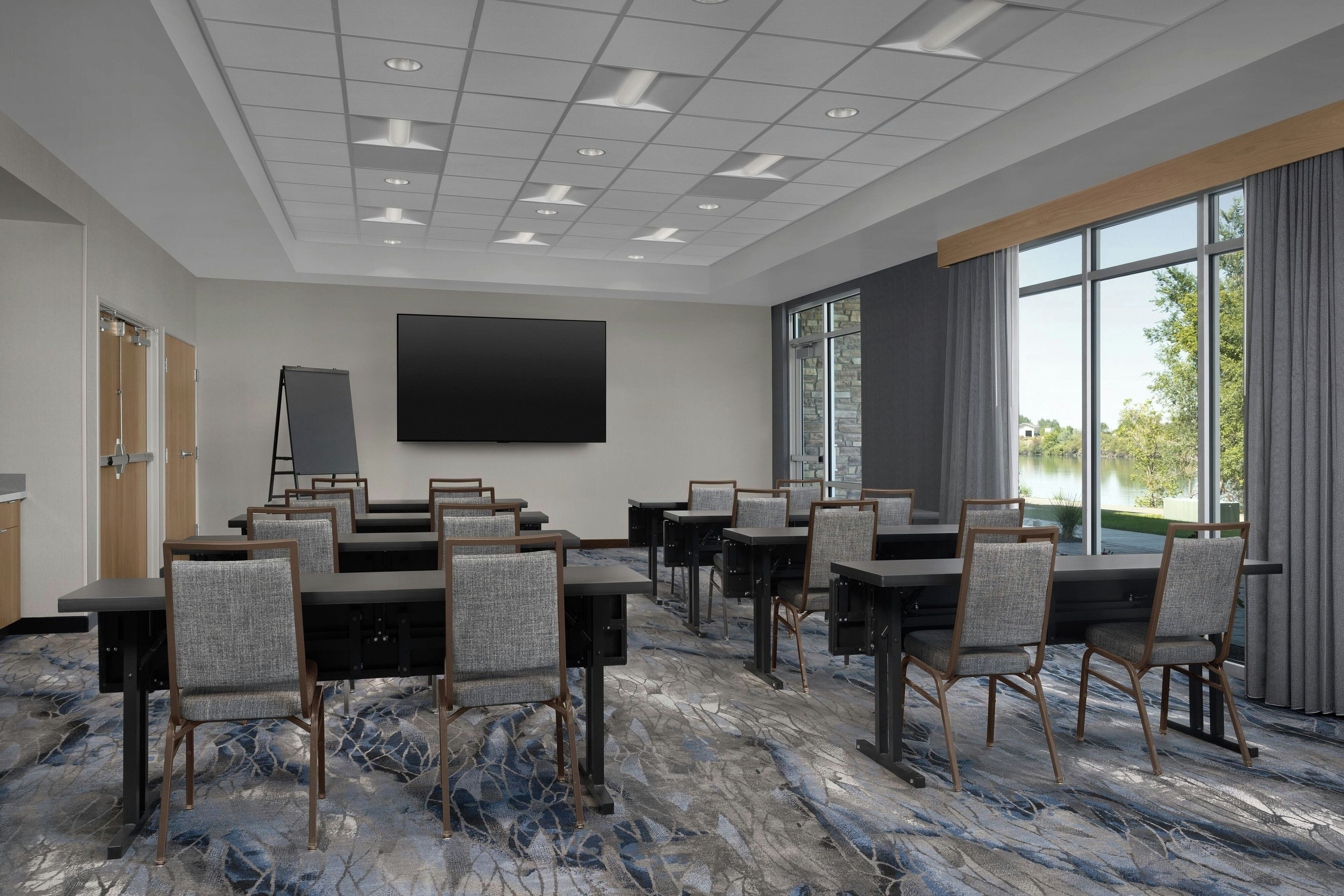Uma sala de conferências com uma tela grande, várias mesas e cadeiras.