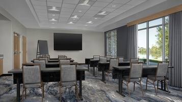 Uma sala de conferências com uma tela grande, várias mesas e cadeiras.