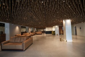 Um hall amplo com design moderno, apresentando uma grande área de estar com sofás e um teto alto com um lustre pendente exclusivo.