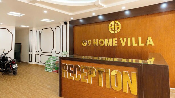 Uma receção com a identificação 'RECEPTION' e 'G9 HOME VILLA', uma scooter e caixas empilhadas num espaço moderno.