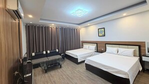 Quarto de hotel com duas camas, um sofá, uma escrivaninha e um ar condicionado.