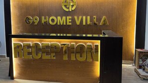 Um balcão de recepção com a identificação 'G9 HOME VILLA' e 'RECEPÇÃO'.