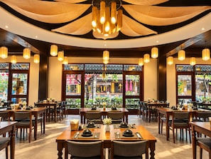 Restaurante com várias mesas, cadeiras e um lustre central.