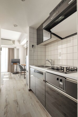 Cozinha moderna com fogão a gás, eletrodomésticos em aço inoxidável e painel de azulejos.