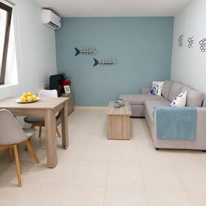 Uma sala de estar moderna com área de jantar, sofá e mesa de centro.
