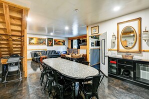 Uma sala de jantar com uma mesa comprida, cadeiras, teto de madeira e obras de arte nas paredes.