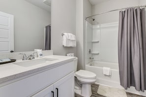Casa de banho com lavatório branco, sanita e banheira.