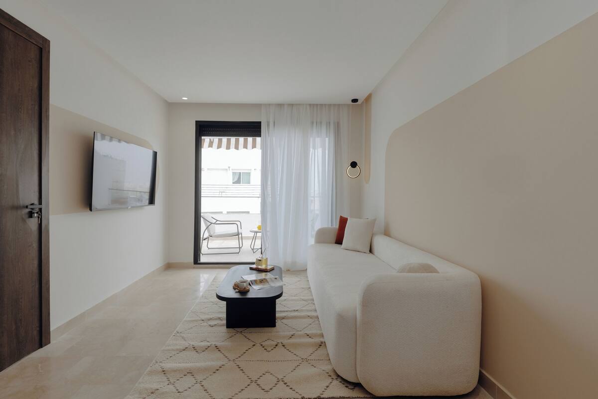 Uma sala de estar moderna com um sofá, uma mesa de centro e uma TV fixada na parede.