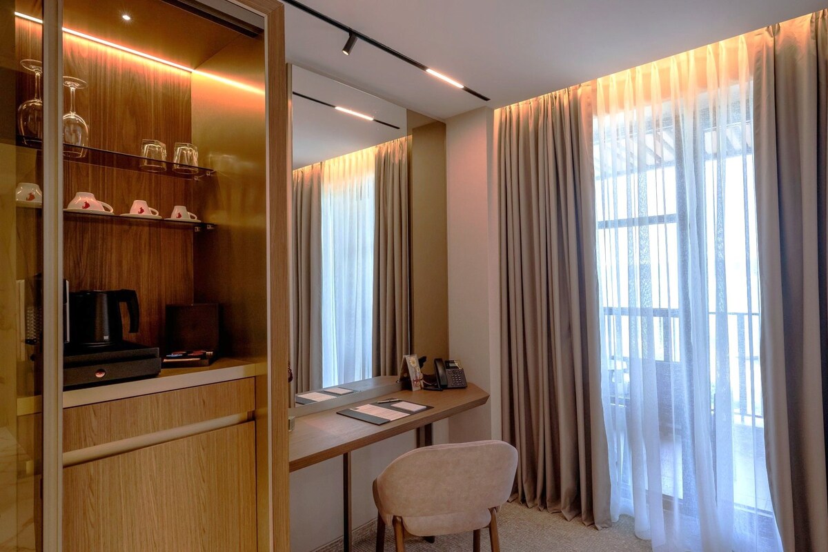Quarto de hotel com escrivaninha, cadeira e minibar.
