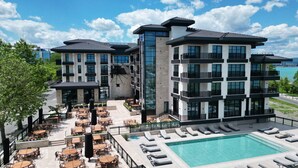 Um hotel com vários andares, piscina no terraço, área de estar externa e vista para a água.