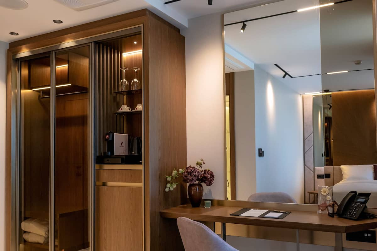 Quarto de hotel moderno com escrivaninha, cadeira, guarda-roupa e um espelho grande.