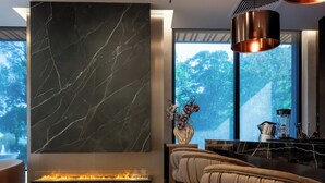 Uma cozinha moderna com painel de fundo de mármore, fogão embutido e área de bar com banquetas.