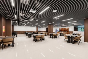 Uma sala de conferências moderna com mesas e cadeiras, teto de madeira e uma estante ao fundo.