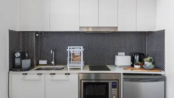 Uma cozinha compacta com micro-ondas, cafeteira, torradeira e uma pia pequena.