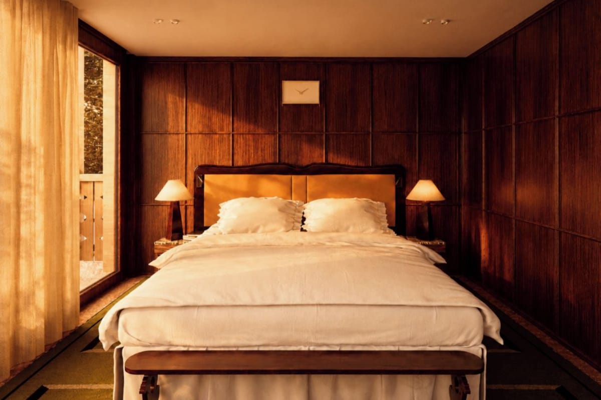 Quarto de hotel com uma cama grande, painéis de madeira nas paredes, uma janela com cortinas e duas luminárias de cabeceira.