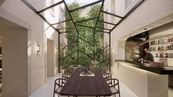 Um interior moderno com uma mesa de jantar comprida, um espaço de bar e vista através de uma estrutura de vidro geométrica.