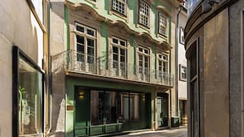 Um edifício com fachada verde, janelas amplas e uma varanda com grades de metal ornamentadas.