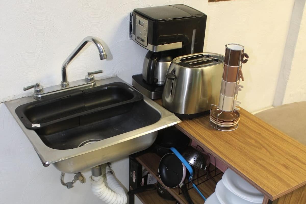 Uma cozinha compacta com pia, torradeira, cafeteira e fogão pequeno.