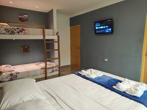 Um quarto com beliches, uma televisão na parede e uma porta.