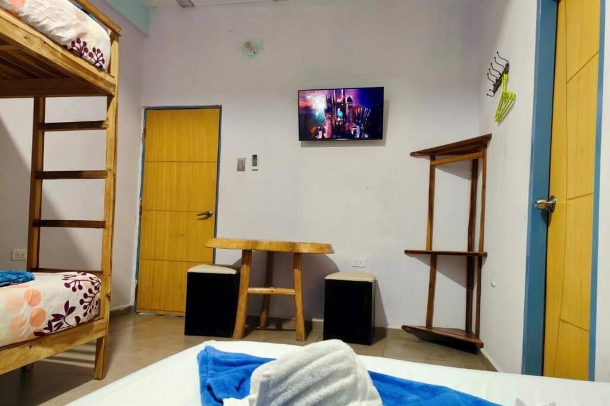 Quarto com beliches, escrivaninha, caixas de som e televisão.