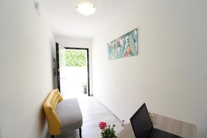 Quarto com escrivaninha, cadeira e um quadro na parede.