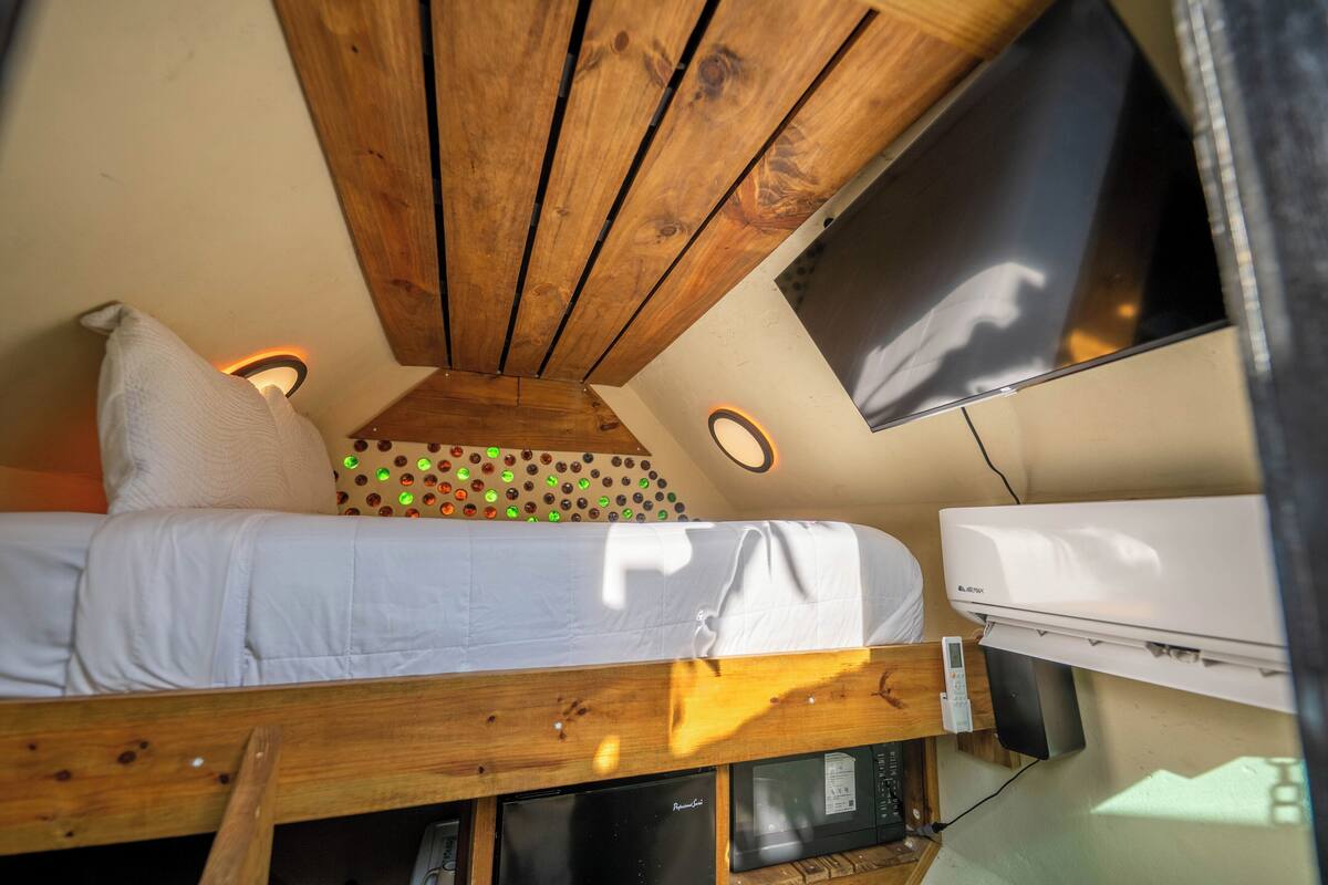 Interior compacto de uma RV com beliche, televisão montada e ar condicionado integrado.
