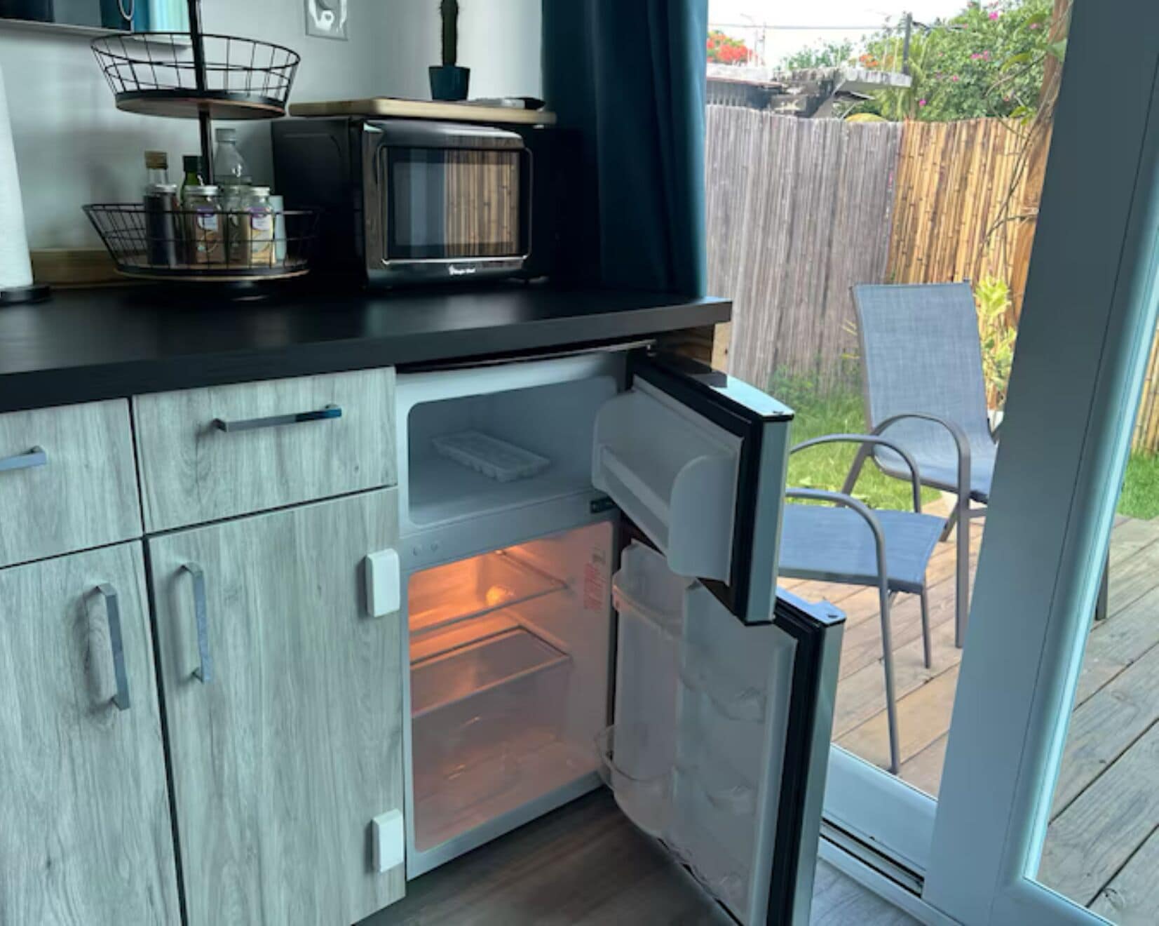 Uma cozinha compacta com geladeira embutida, micro-ondas e uma pia pequena.