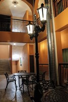 Um pátio interno com escadaria, uma mesa redonda de metal com cadeiras e um candeeiro.
