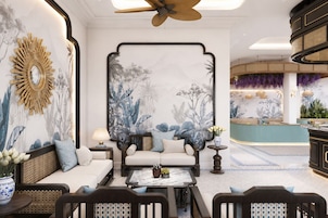 Um hall de hotel moderno com um conjunto de sofás, uma mesa de centro e um espelho decorativo.
