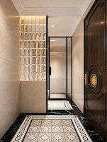 Um corredor com piso estampado, parede com luminária e porta com puxador decorativo.