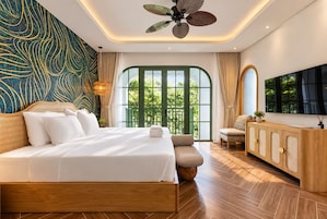 Quarto de hotel moderno com cama grande, televisão, armário e vista para vegetação pela janela.