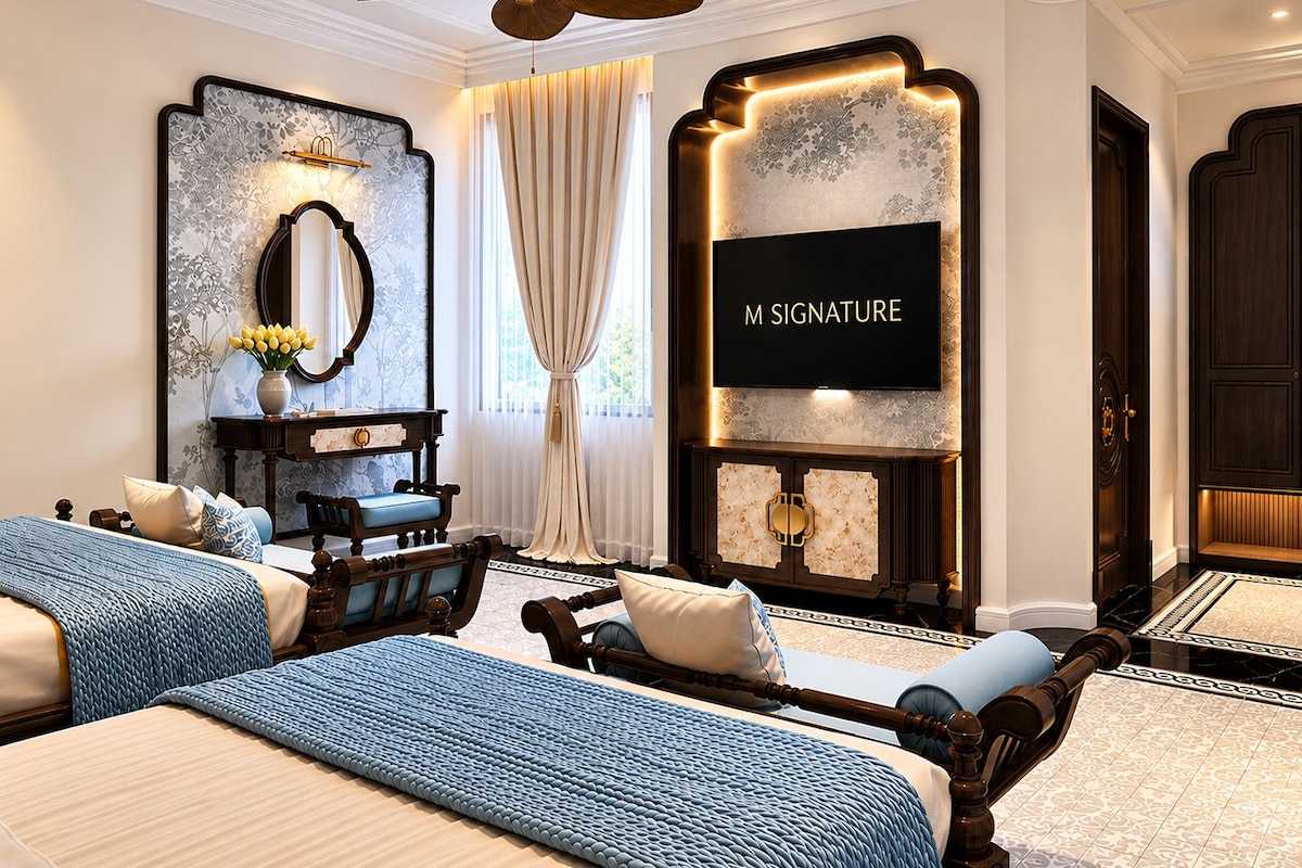Quarto de hotel com duas camas, toucador com espelho, televisão e um grande painel decorativo.