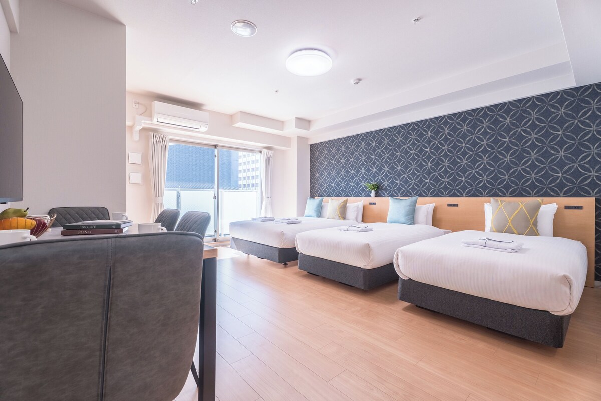 Quarto de hotel com duas camas, um espaço de refeições e vista para a cidade.