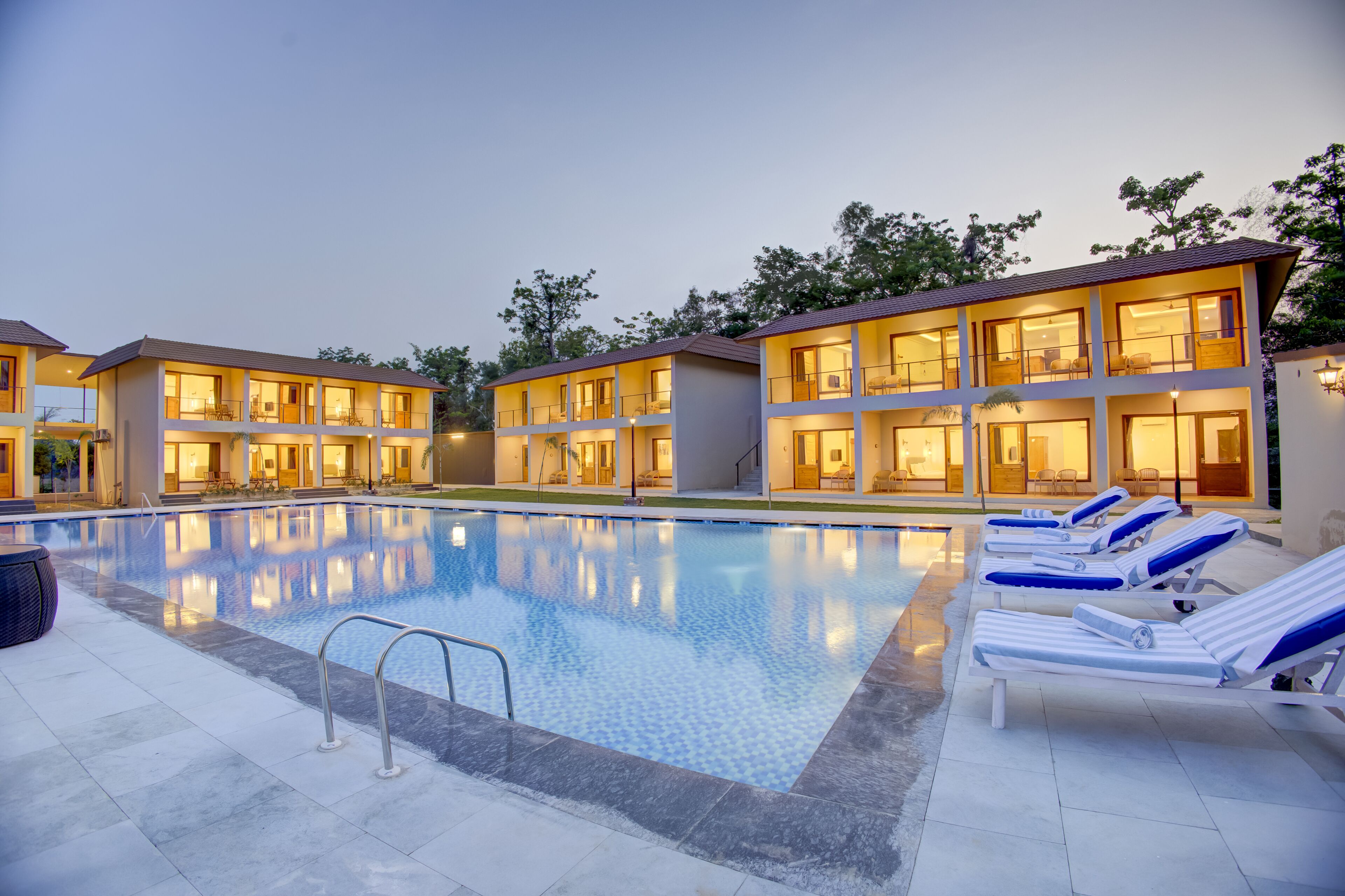 Um hotel de vários andares com piscina e espreguiçadeiras.