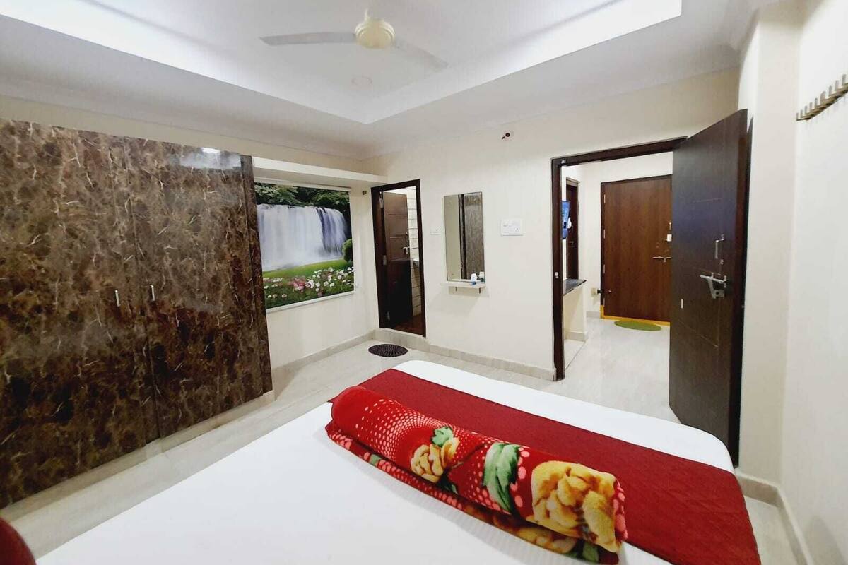 Quarto com uma cama, um guarda-roupa, um espelho e uma porta que dá para outro cômodo.