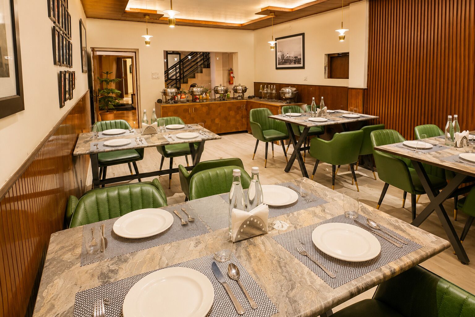 Um restaurante com várias mesas, cadeiras estofadas em verde e um bar ao fundo.