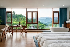 Quarto com uma janela grande, banheira, cama, mesa e cadeira.