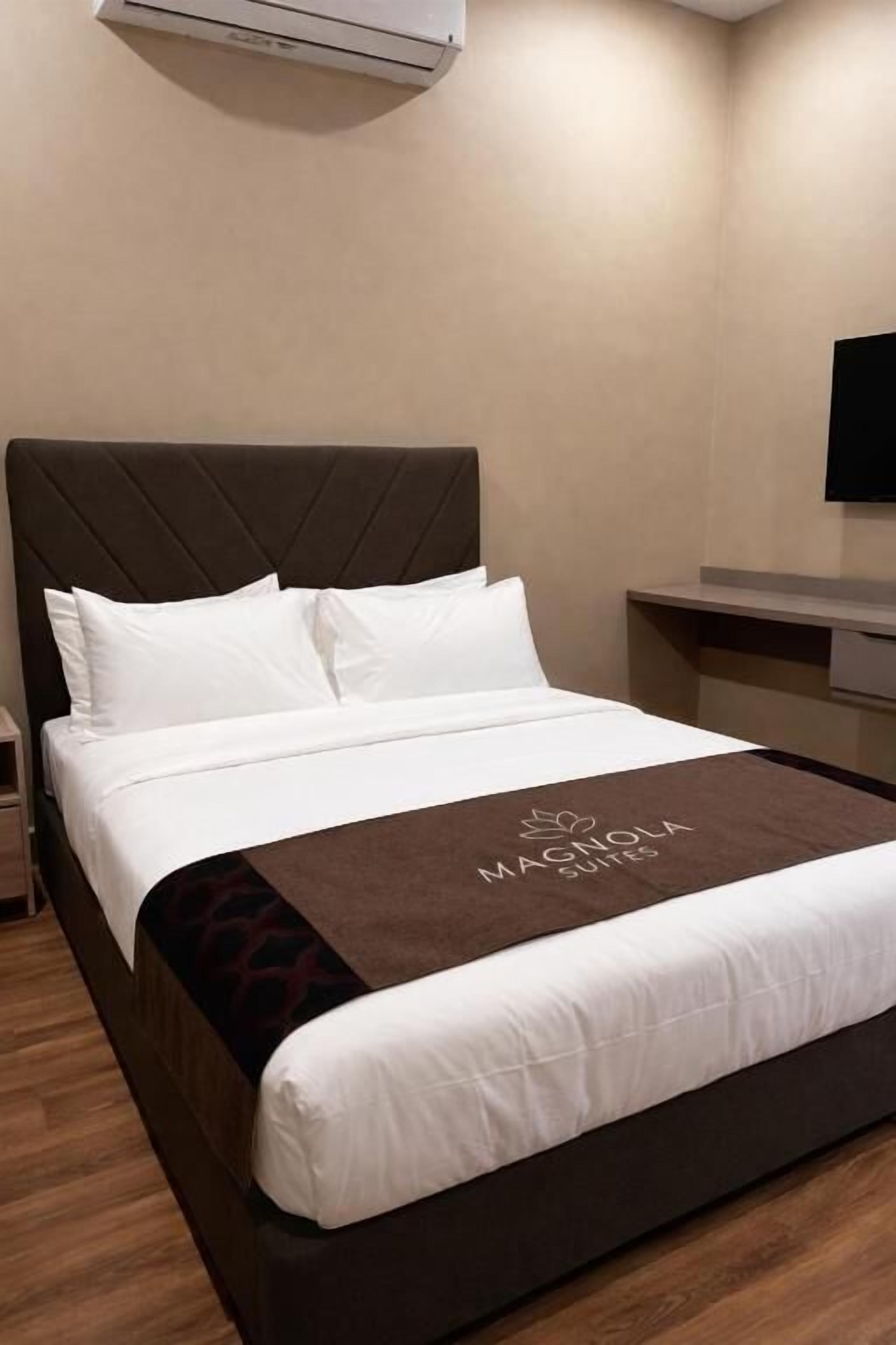 Quarto de hotel com cama, mesa de cabeceira, televisão de tela plana e aparelho de ar condicionado.