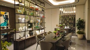 Uma sala de jantar moderna com uma mesa comprida, cadeiras e uma estante cheia de objetos decorativos.