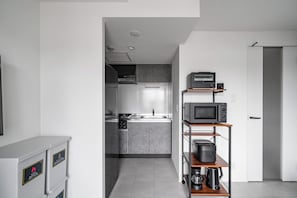 Uma cozinha moderna com eletrodomésticos de aço inoxidável, micro-ondas, cafeteira e pia.