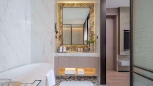 Um banheiro moderno com parede de mármore, um espelho grande, uma banheira e um piso estampado.