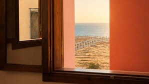 Quarto com uma grande janela com vista para uma praia e o oceano.