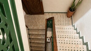Uma escadaria com azulejos estampados e um corrimão de metal verde.