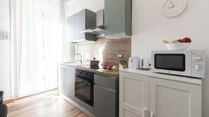Uma cozinha moderna com micro-ondas, torradeira e chaleira sobre a bancada, fogão e pia.