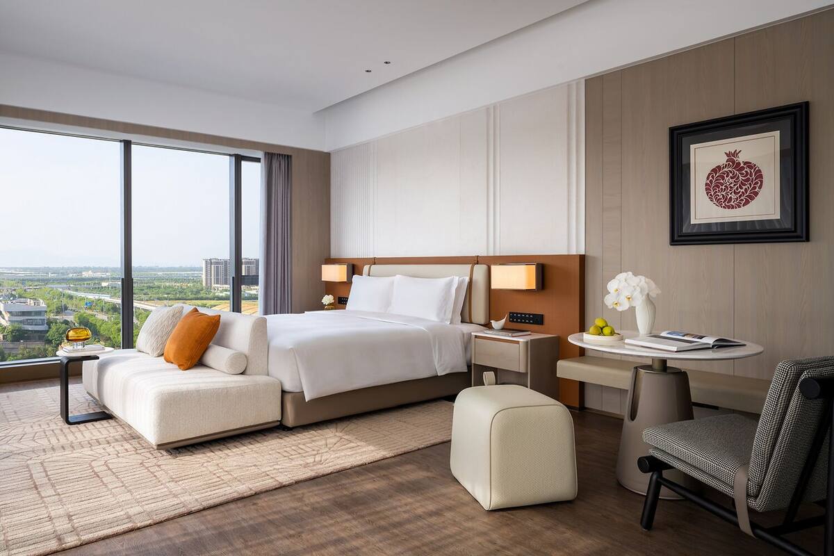 Quarto de hotel moderno com uma cama grande, um sofá, uma escrivaninha e uma cadeira.