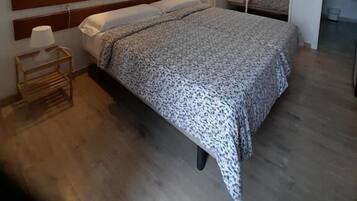 Quarto com cama, luminária de cabeceira, luz na parede e espelho.